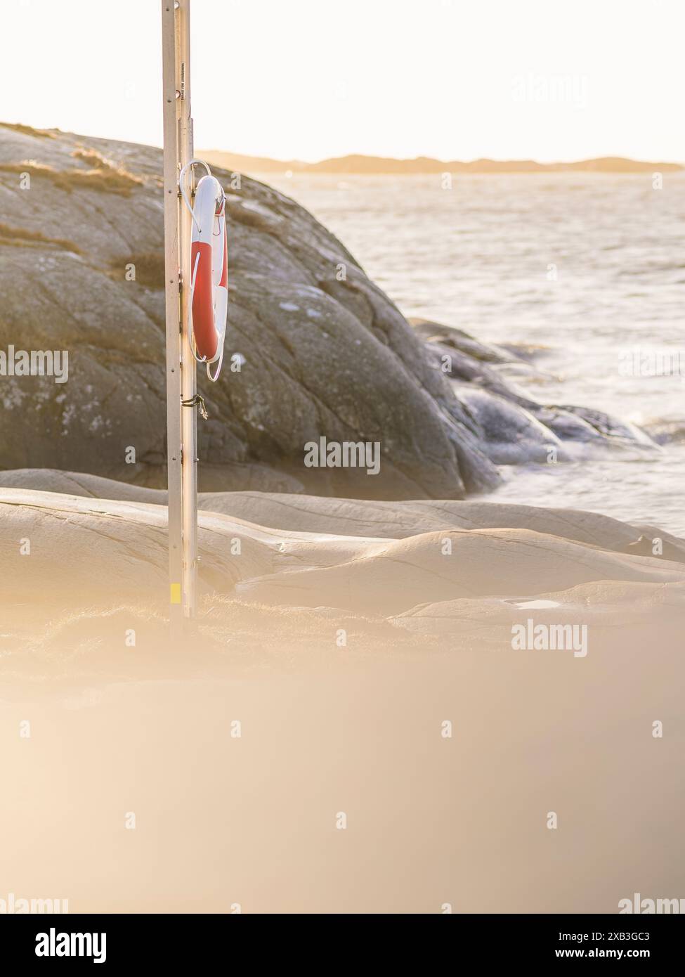 Inflatable life buoy on pole at beach during sunset Stock Photo - Alamy