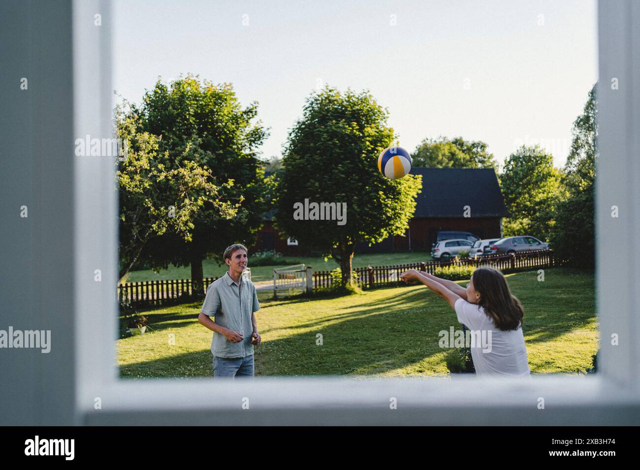 Young friends playing volleyball seen through window Stock Photo - Alamy