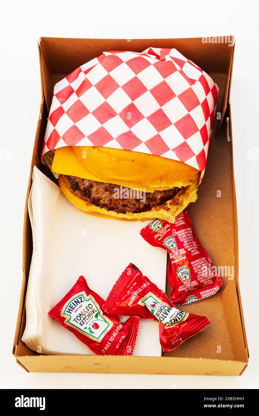 Classic American cheese burger in box with napkin and sachets of Heinz ...