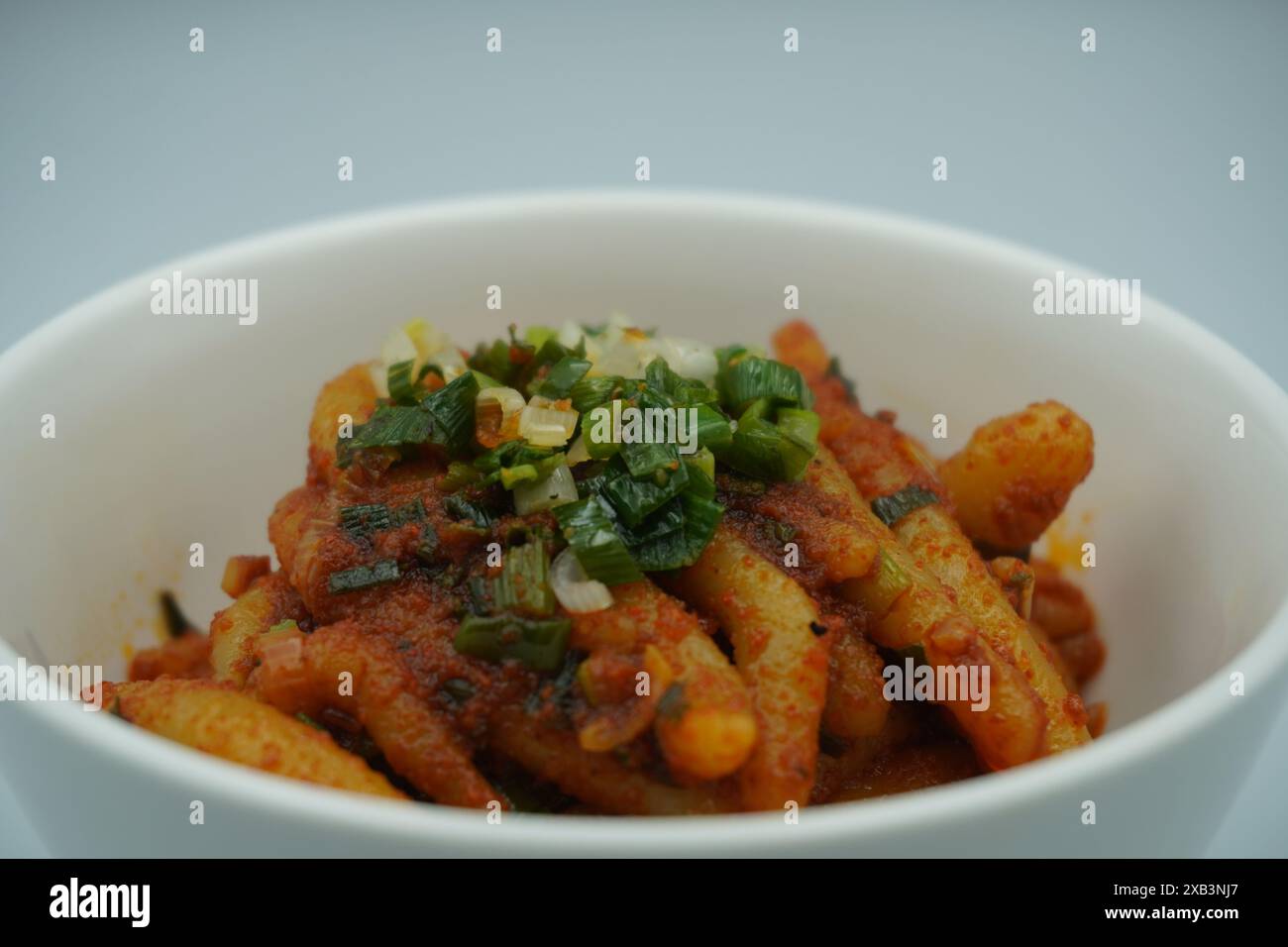 A bowl of spicy lou shu fan with spring onions on top and white ...