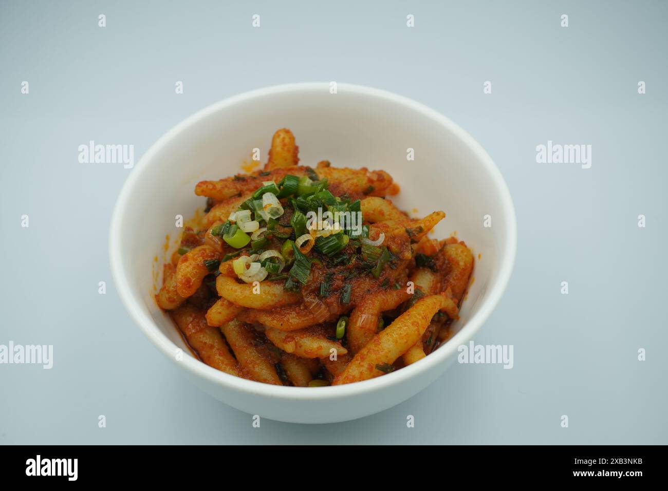 A bowl of spicy lou shu fan with spring onions on top and white ...