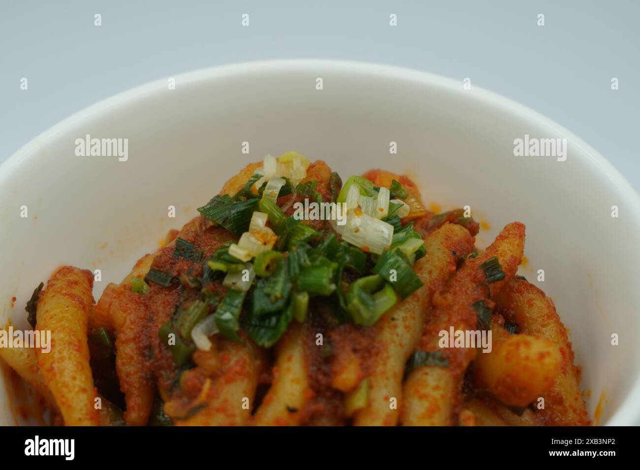 A bowl of spicy lou shu fan with spring onions on top and white ...