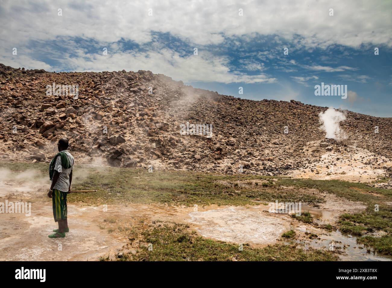 Local tour guide traditionally dressed showing hot geothermal volcanic ...