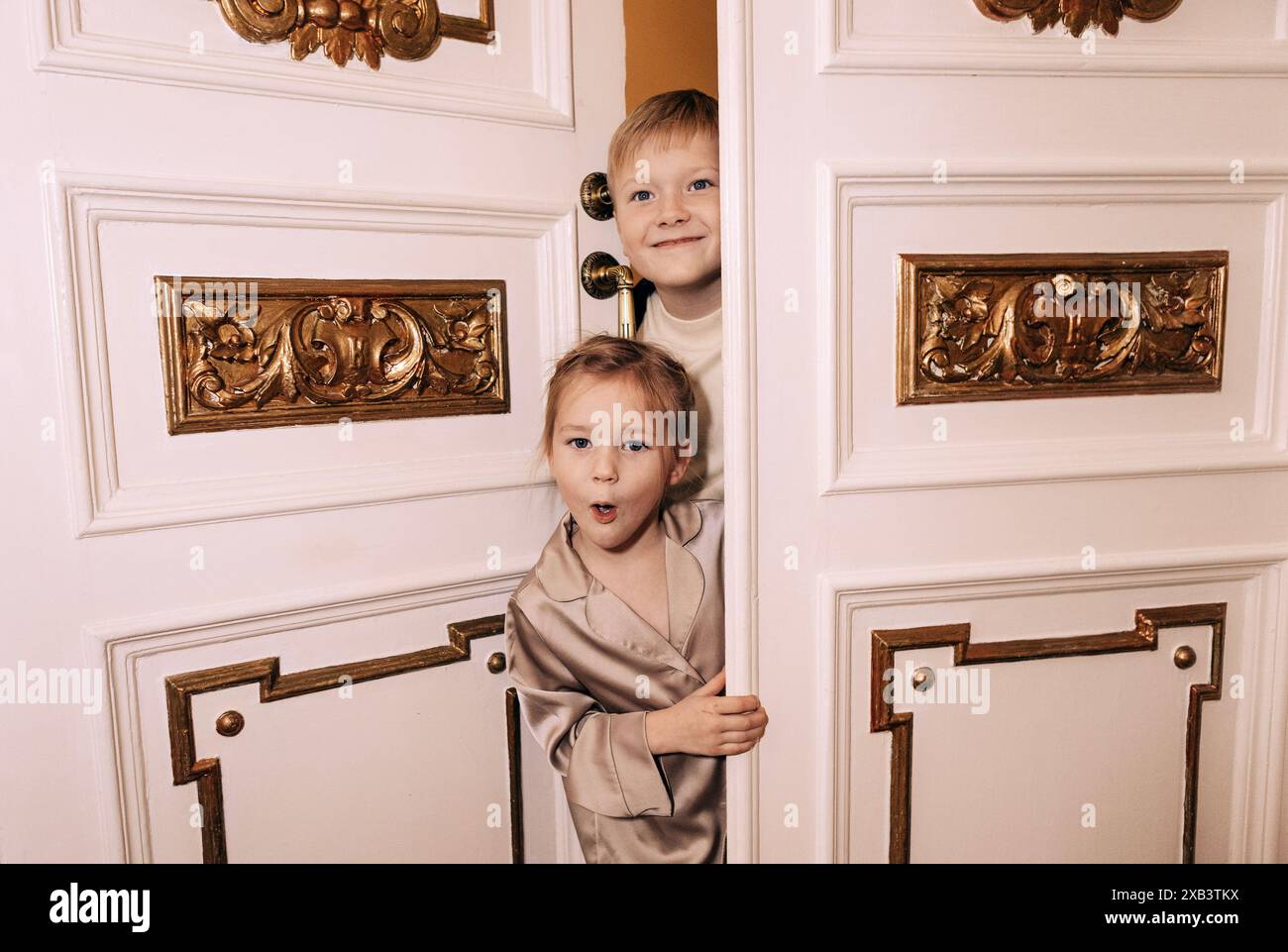 Cute sibling peeping from behind the living room door. Happy brother ...