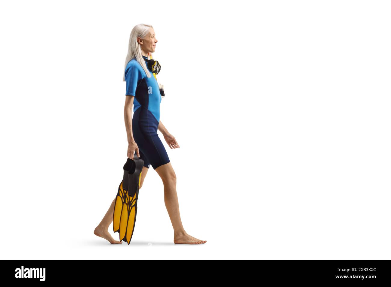 Full length profile shot of a woman in a diving suit carrying fins and ...