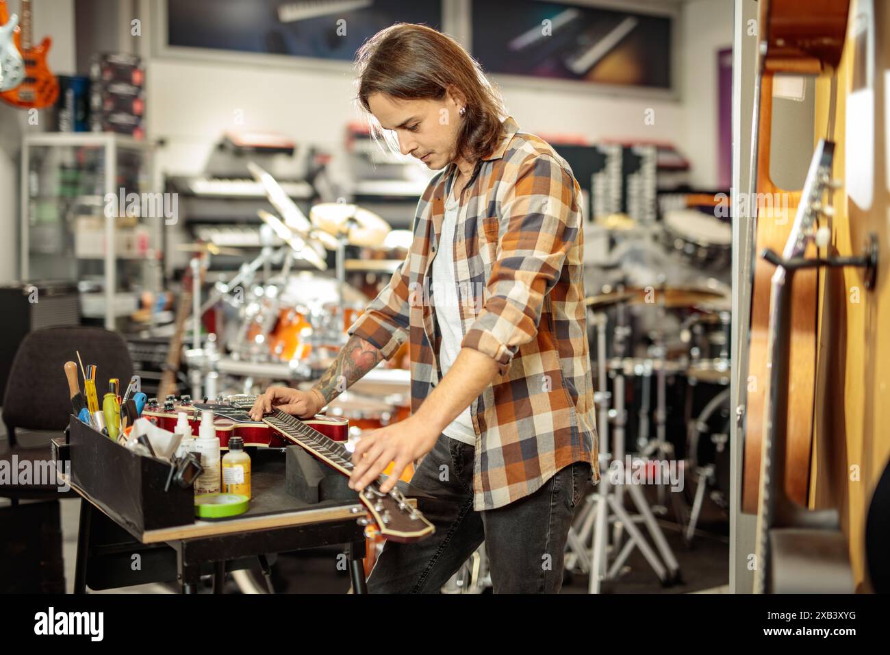 Man fixing an electric guitar in a music workshop Stock Photo - Alamy