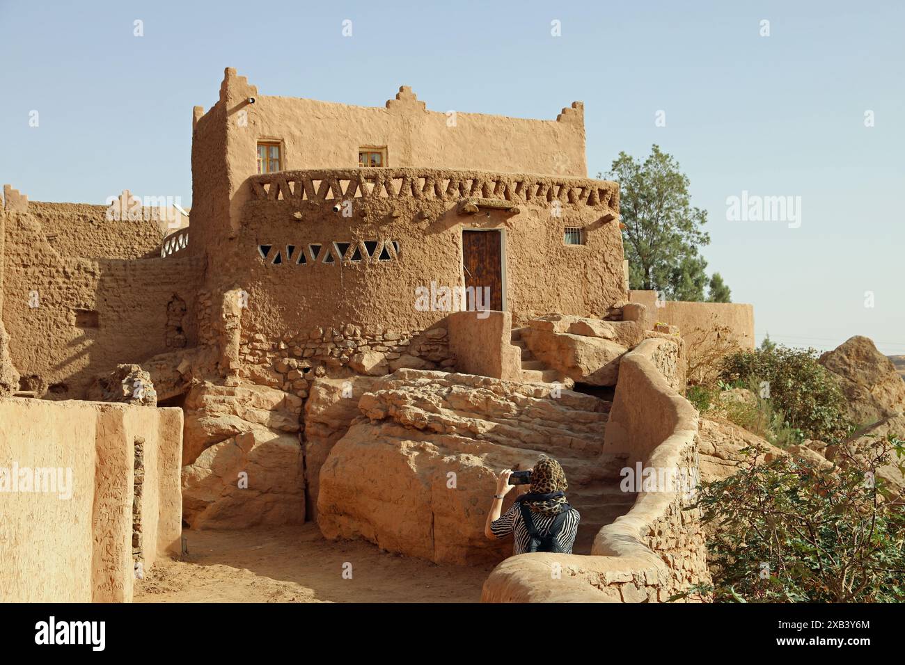 Tourist taking a photo of a mudbrick house in the ksar of Taghit in ...