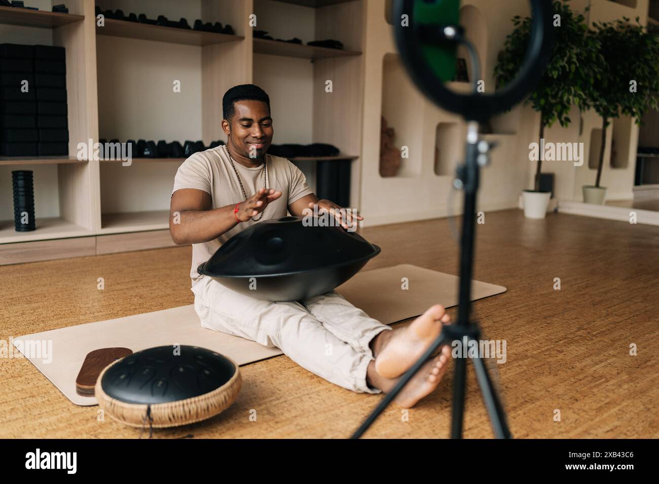 Wide shot of happy smiling African male blogger practicing native music ...