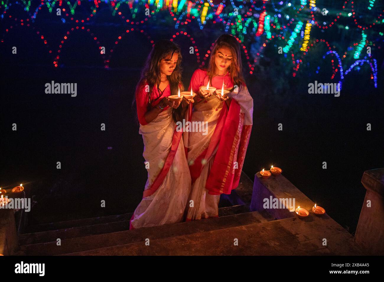 Young women illuminate Diwali lamps at the pond of Sri Sri Baradeswari ...