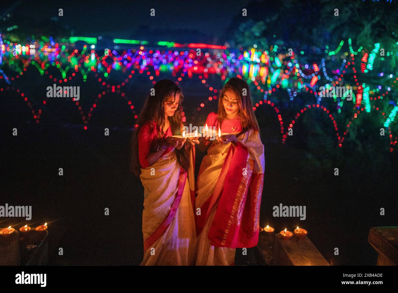 Young women illuminate Diwali lamps at the pond of Sri Sri Baradeswari ...