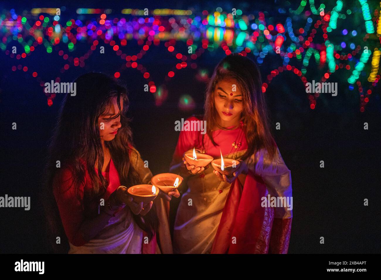 Young women illuminate Diwali lamps at the pond of Sri Sri Baradeswari ...