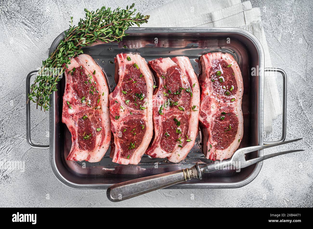 Marinated Raw meat of lamb mutton saddle in steel tray with thyme ...