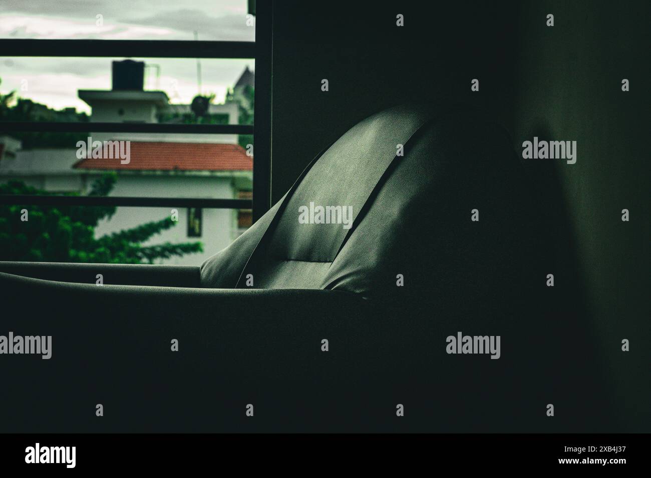 A single, antique chair with rolled arms sits in a dark room ...