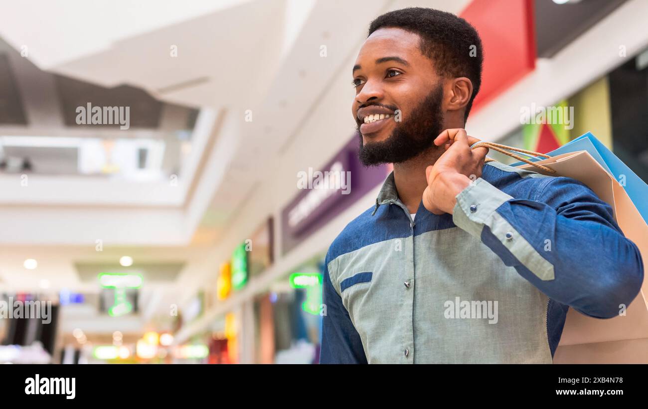 Cheerful Black Man Holding Shopping Bags in a Mall Stock Photo - Alamy