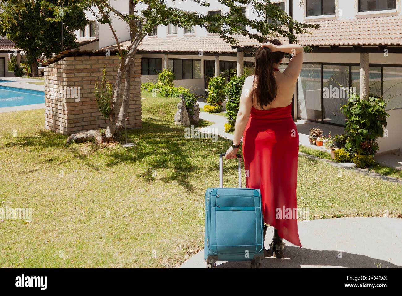 Caucasian female guest holding her suitcase arriving at the resort ...