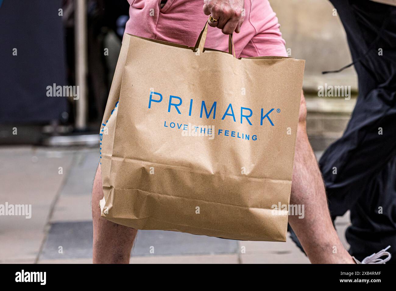 Male person walking carrying a branded carrier bag from high-street ...
