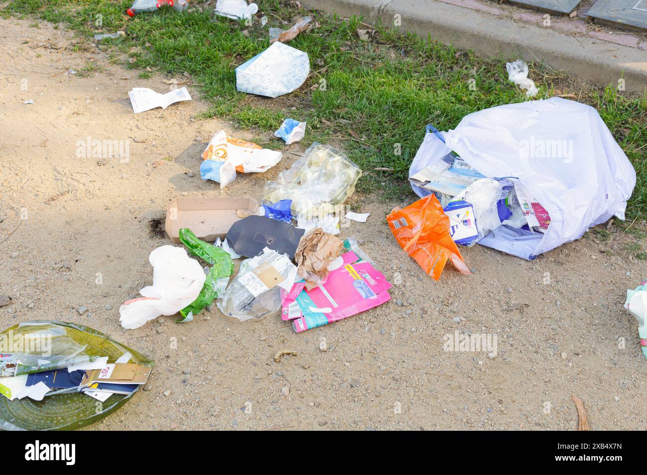 Close up of trash bags thrown and open on street next to trash and ...