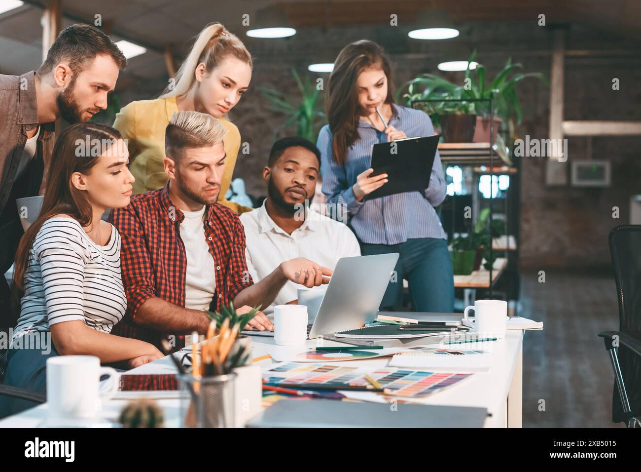Group of People Around Table Looking at Laptop Stock Photo - Alamy