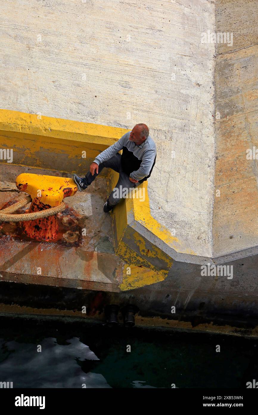 Longshoreman waiting to cast off ship's rope, Symi new harbour, Symi ...
