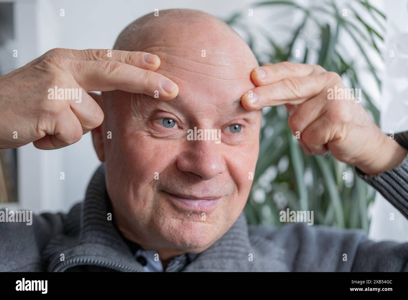 65-year-old man, senior looks carefully examines wrinkles on face, skin ...