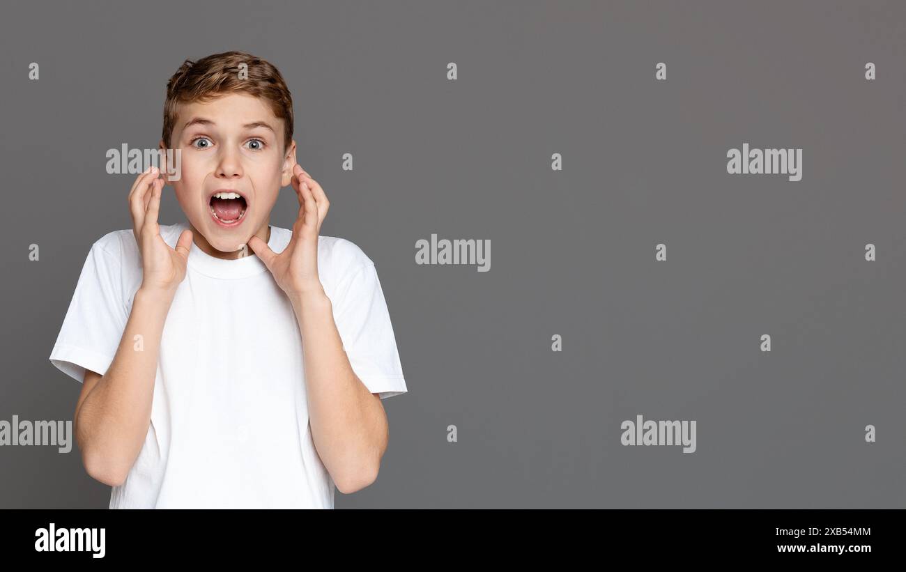 Happy teen boy with shocked expression on grey background Stock Photo ...