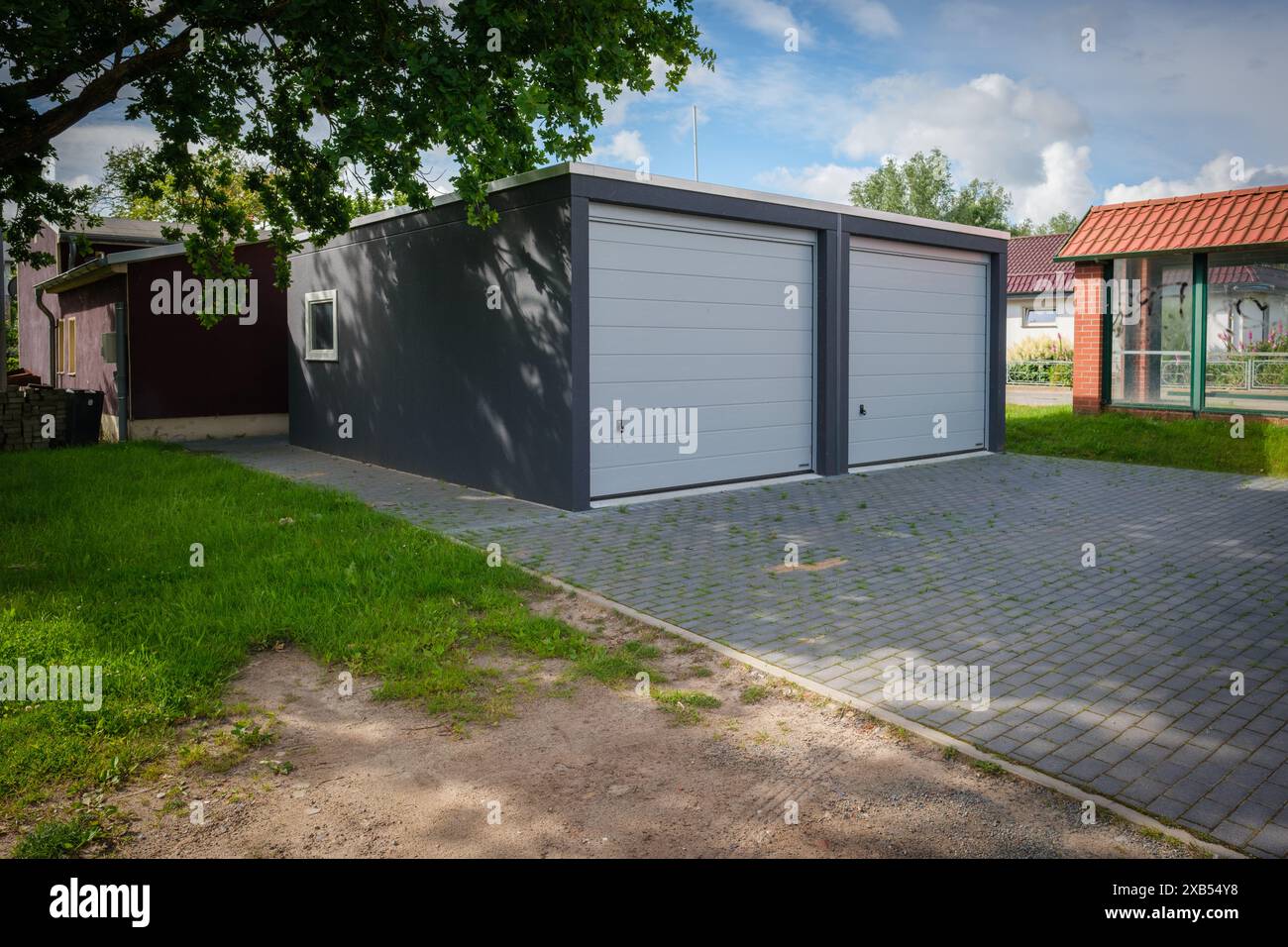Anewly built double garage with roller doors stands under a tree Stock ...
