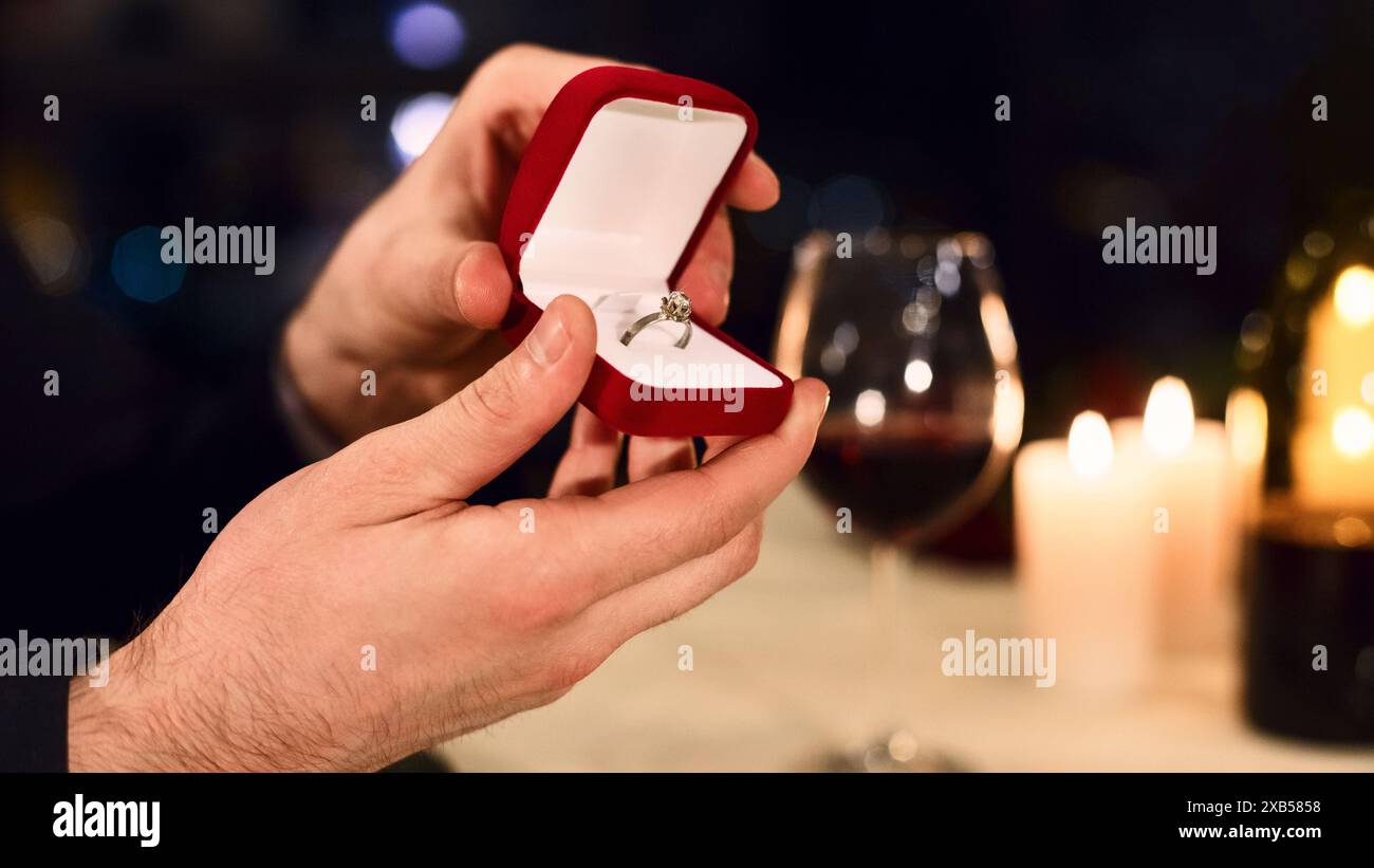 Man's hands holding box with ring making proposal Stock Photo - Alamy