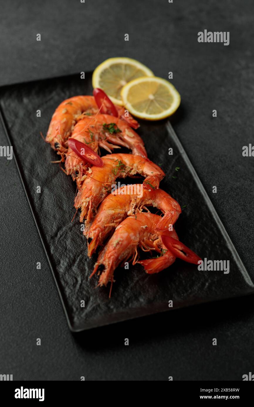 Large cooked king prawns on a black background. Lemon slices Stock ...