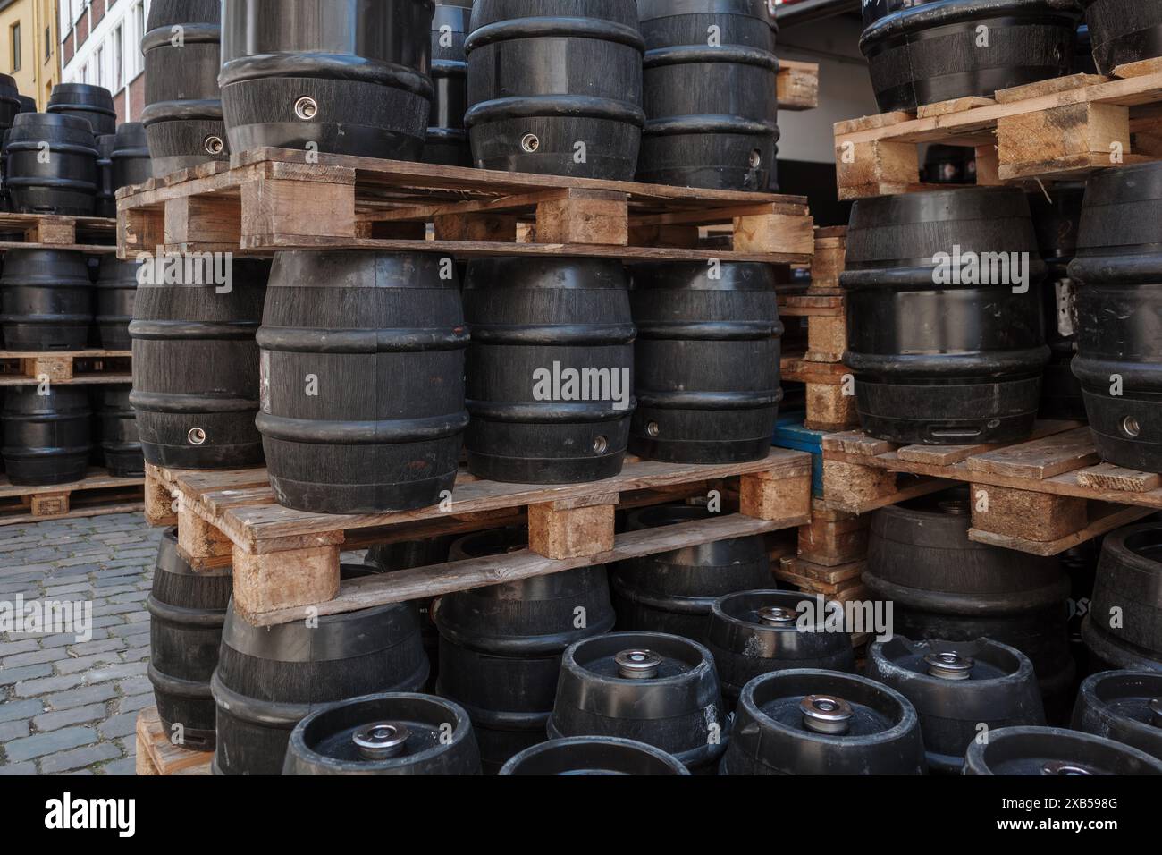 A collection of black barrels neatly stacked on wooden pallets in an ...