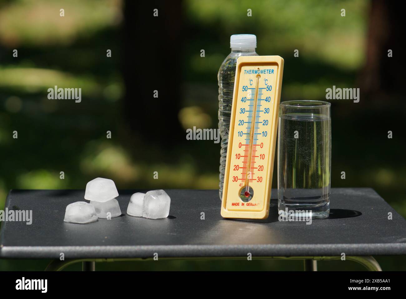 Close up of water in a bottle adn glass, thermometer and melting ice ...