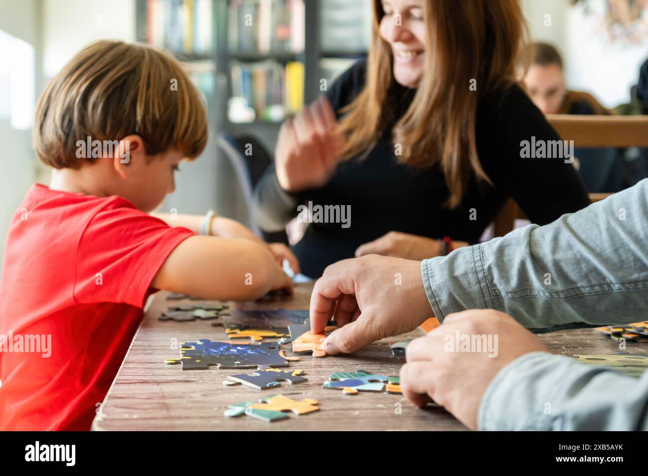 Focused boy assembling jigsaw puzzle with happy crop parents Stock ...