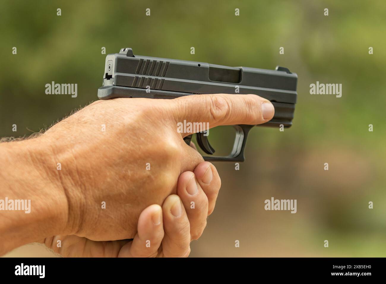 Man's hands showing the proper way to hold a handgun Stock Photo - Alamy