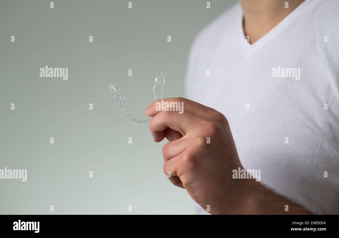 close-up of a young man holding an invisible dental retainer and a case ...