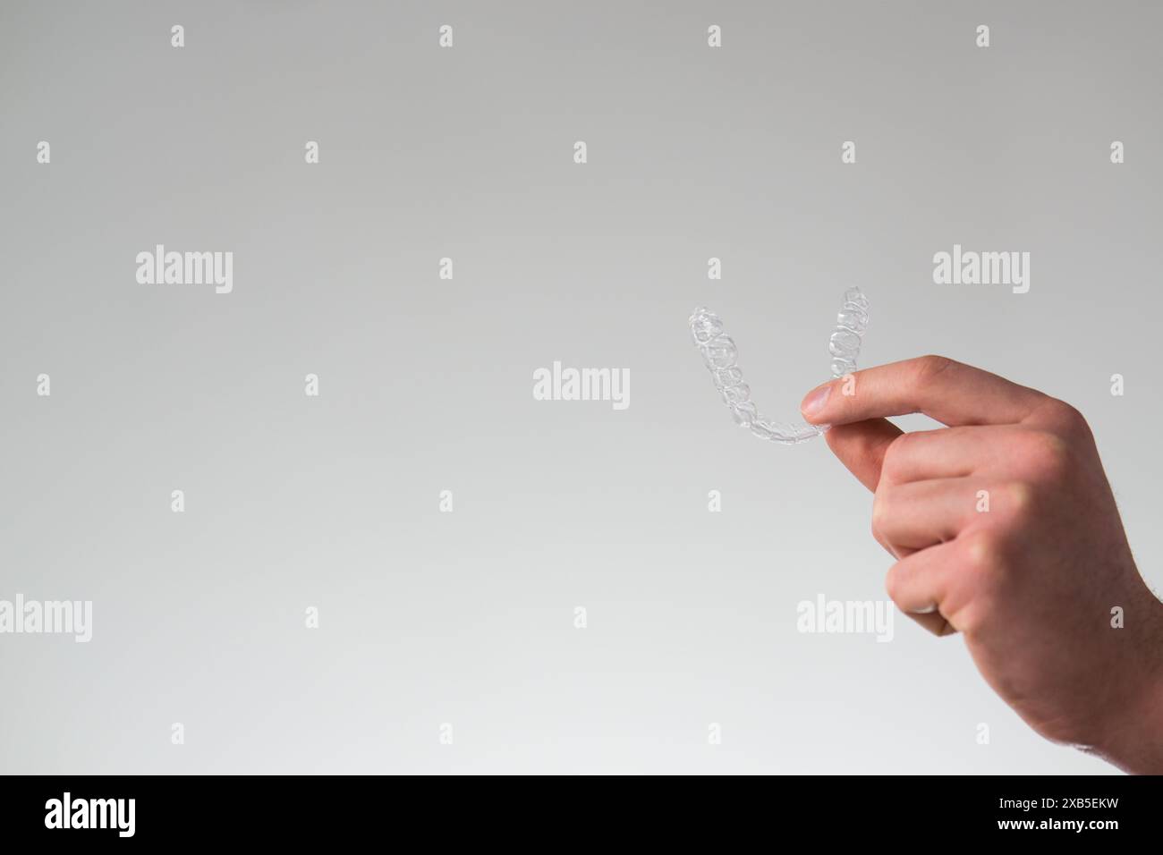close-up of a young man holding an invisible dental retainer and a case ...