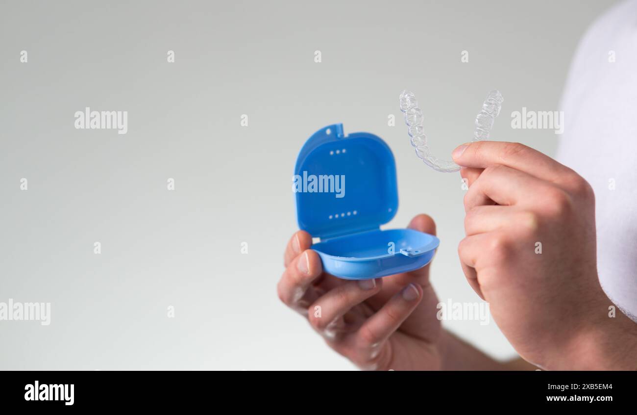 close-up of a young man holding an invisible dental retainer and a case ...