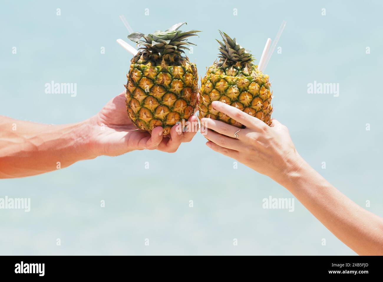 Pina colada in a pineapple in hands of people, celebrating on tropical ...
