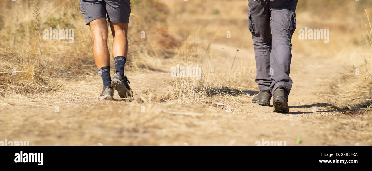 Cinematic cropped photo of two hikers walking on a dirt road in the ...