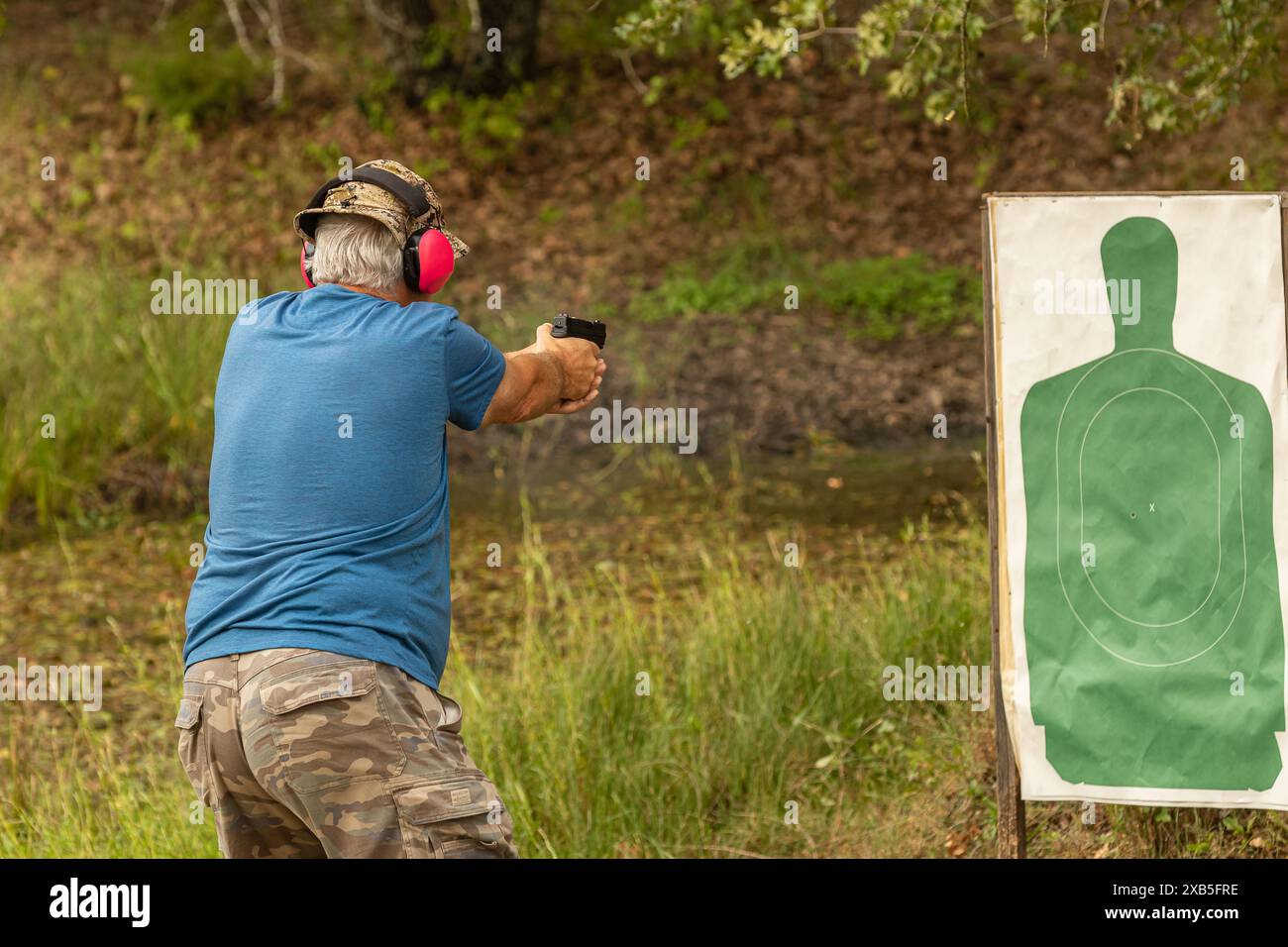 Senior man 70+ is doing target practice with a handgun Stock Photo - Alamy