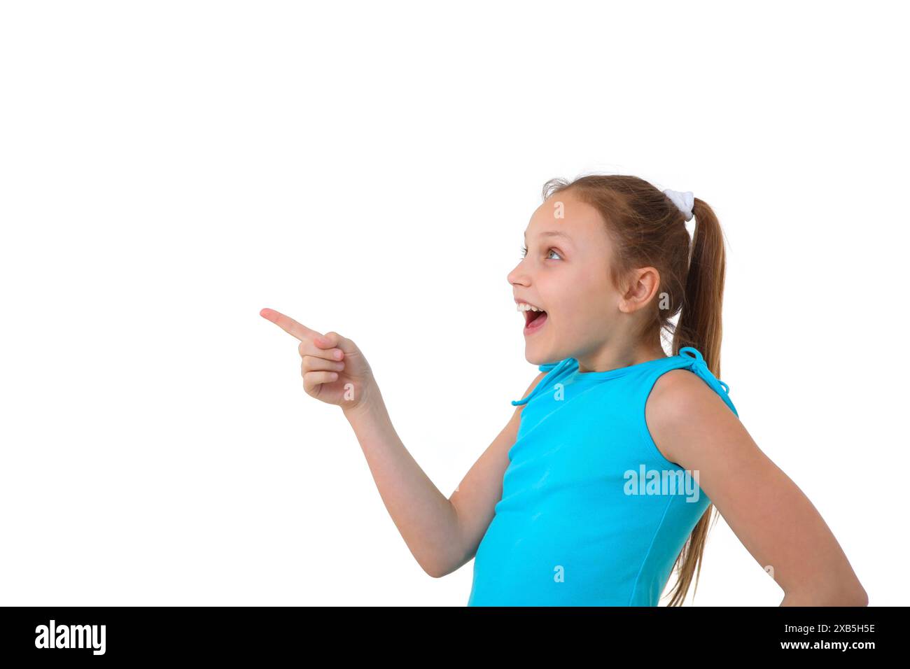 cheerful preteen girl pointing and looking to the side at at copy space ...