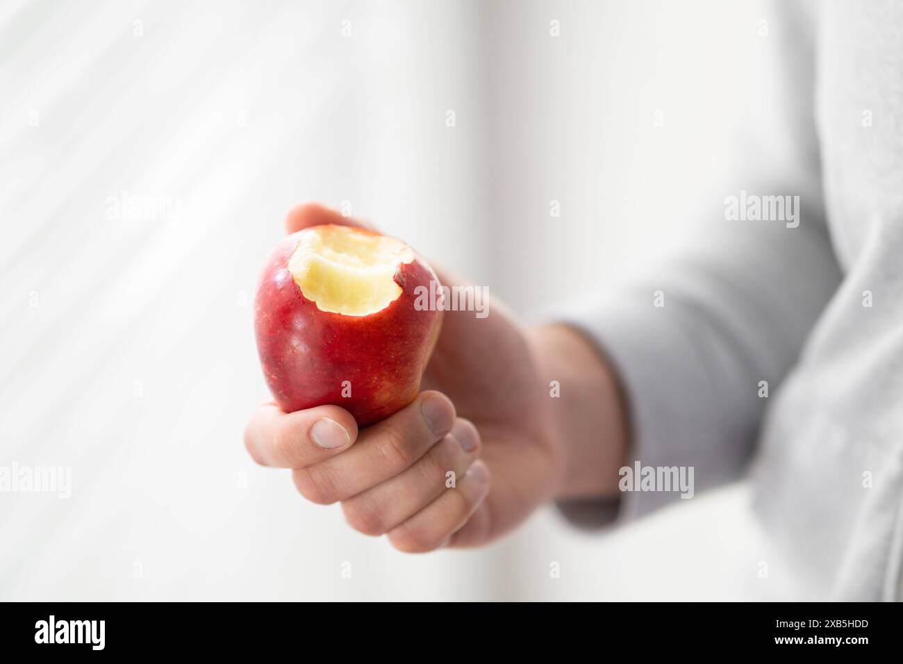 male hand holding bitten apple copy space, man eating an apple close up ...
