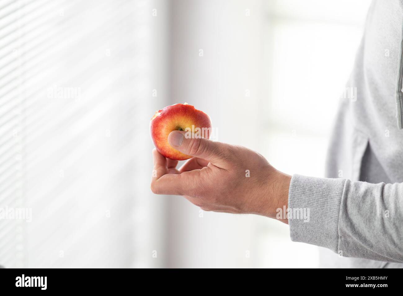 male hand holding bitten apple copy space, man eating an apple close up ...