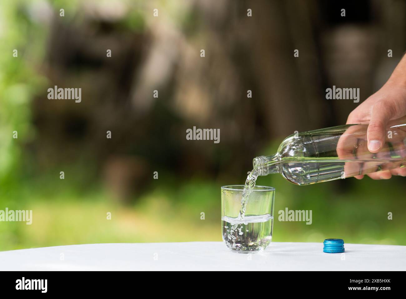 close up of male hand pouring water from bottle into glass, pouring ...