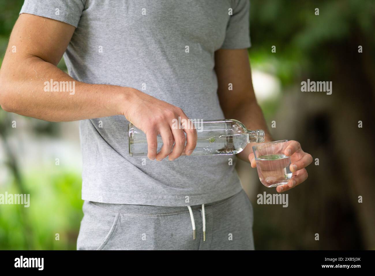 man pouring water from bottle into glass, pouring glass of water, bottle of glass water filling ...
