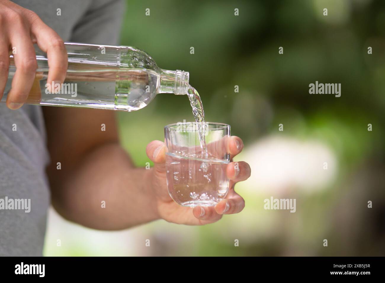 man pouring water from bottle into glass, pouring glass of water, bottle of glass water filling ...