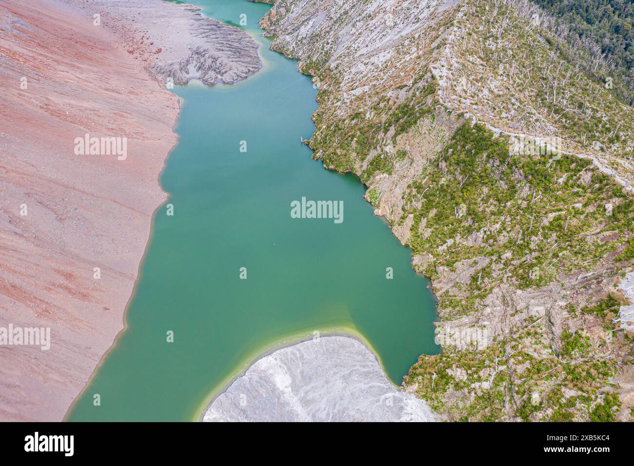 Dead trees, crater rim of chaiten volcano, colored rock, small lake ...