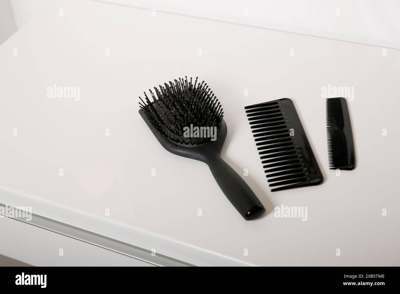 Used hair brush and combs with some hair on white table, head skin ...