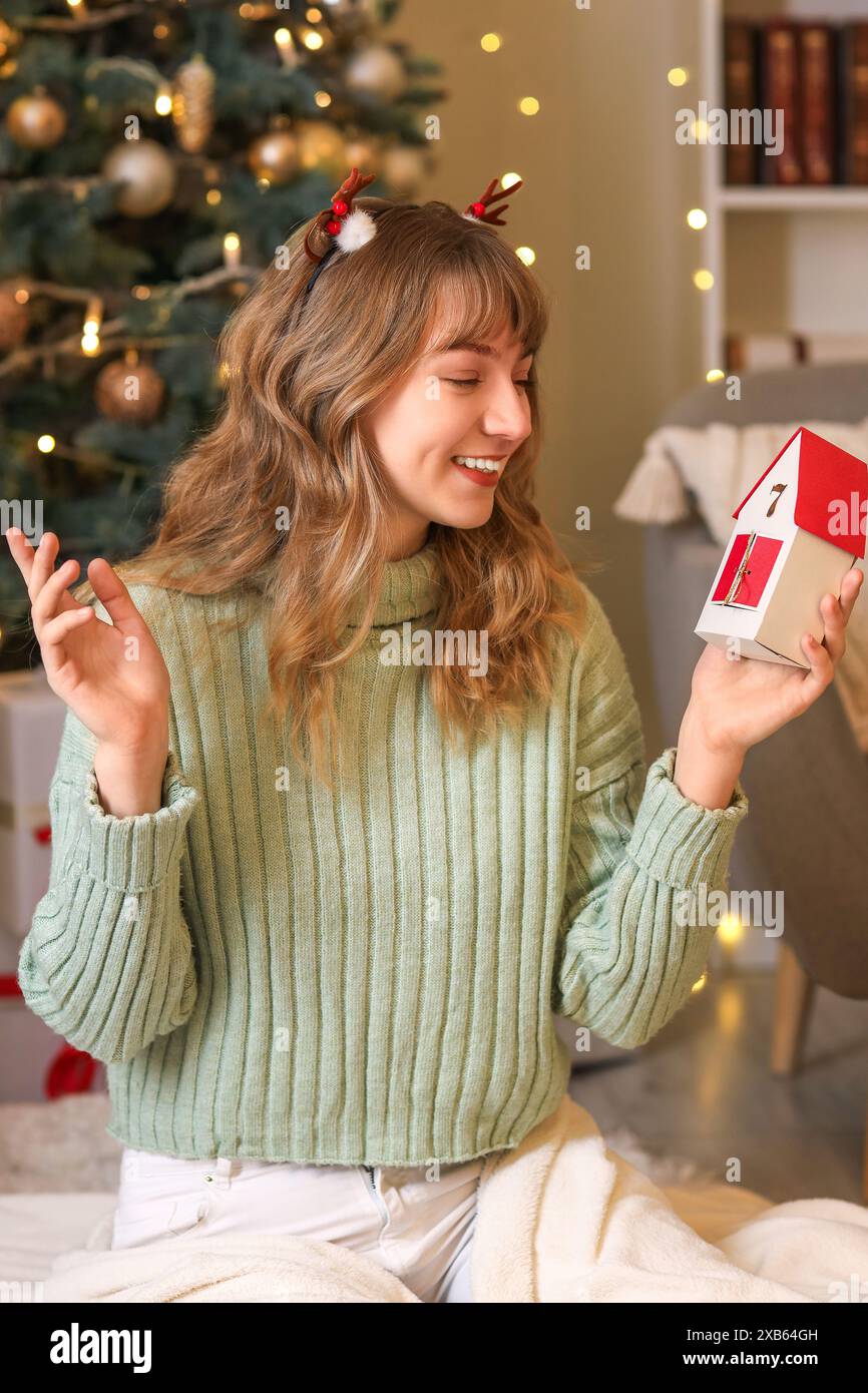 Young woman in reindeer horns with Advent calendar at home on Christmas ...