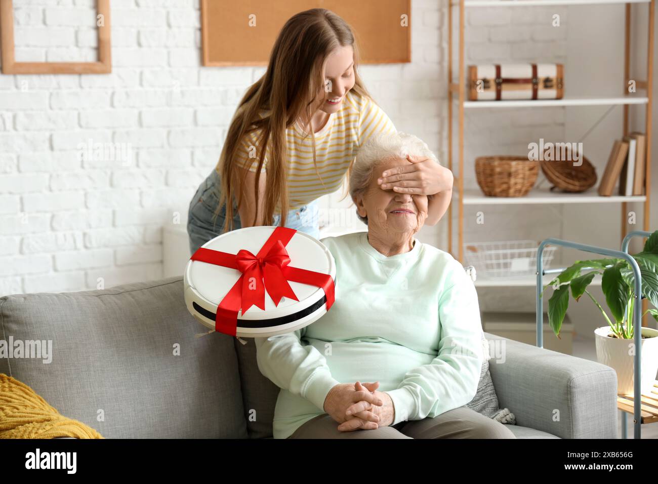 Young woman with wrapped robot vacuum cleaner covering eyes of her ...
