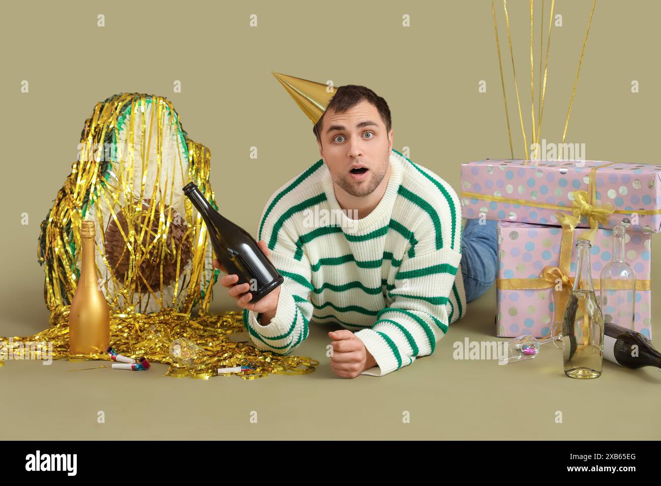 Shocked young man with hangover and bottle lying after Birthday party ...