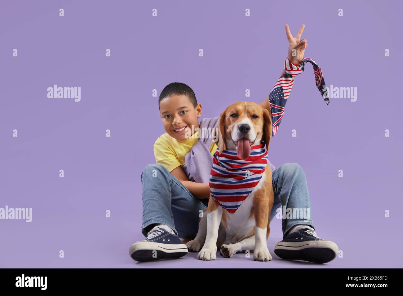 Little African-American boy with cute beagle dog on lilac background ...